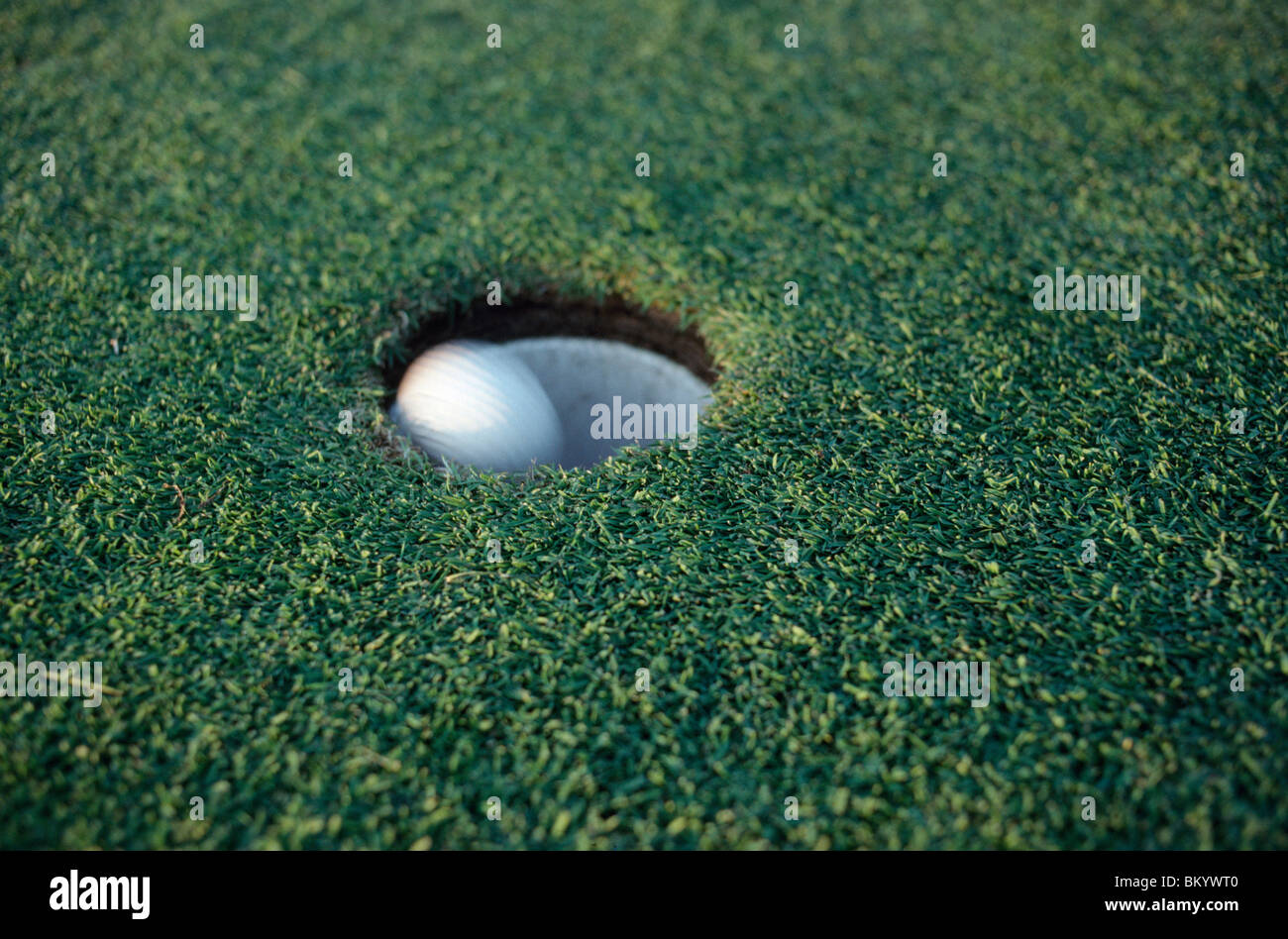 Golf ball falling into hole Stock Photo - Alamy
