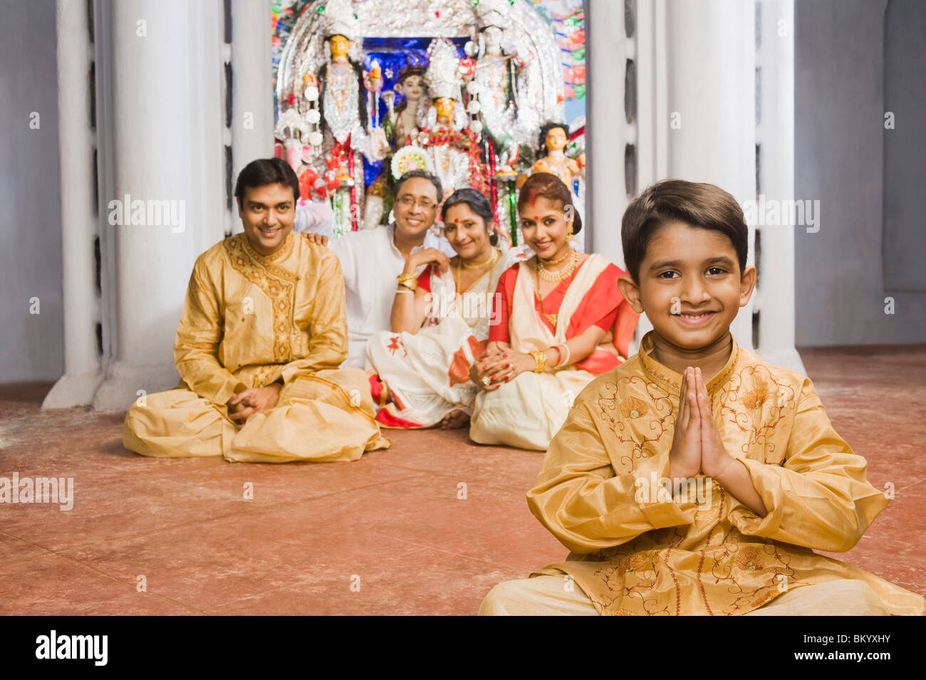 Boy with his family praying in a temple Stock Photo - Alamy