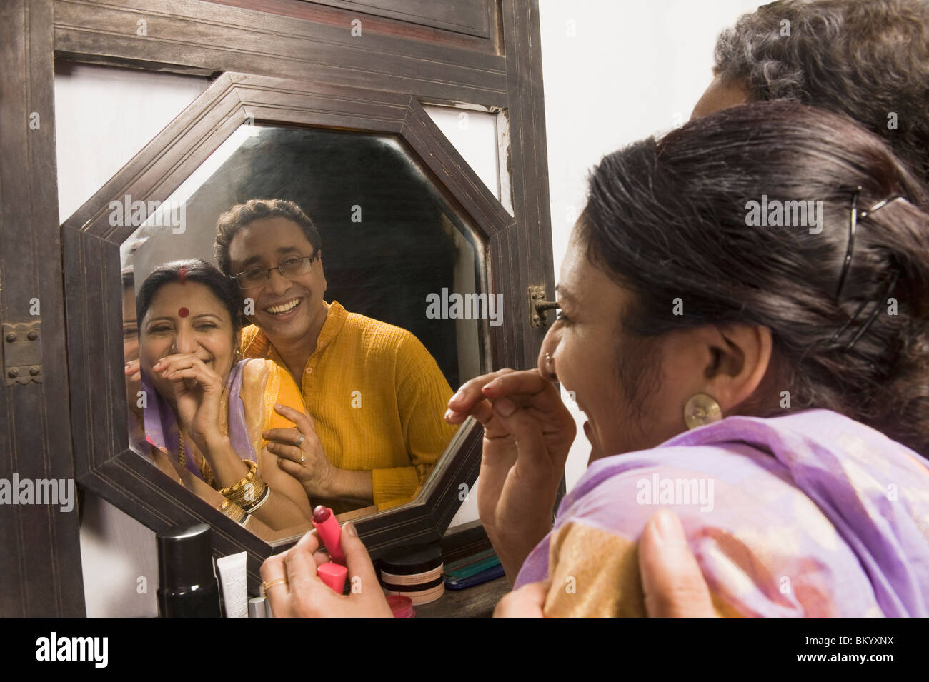 Couple smiling in front of a mirror Stock Photo - Alamy