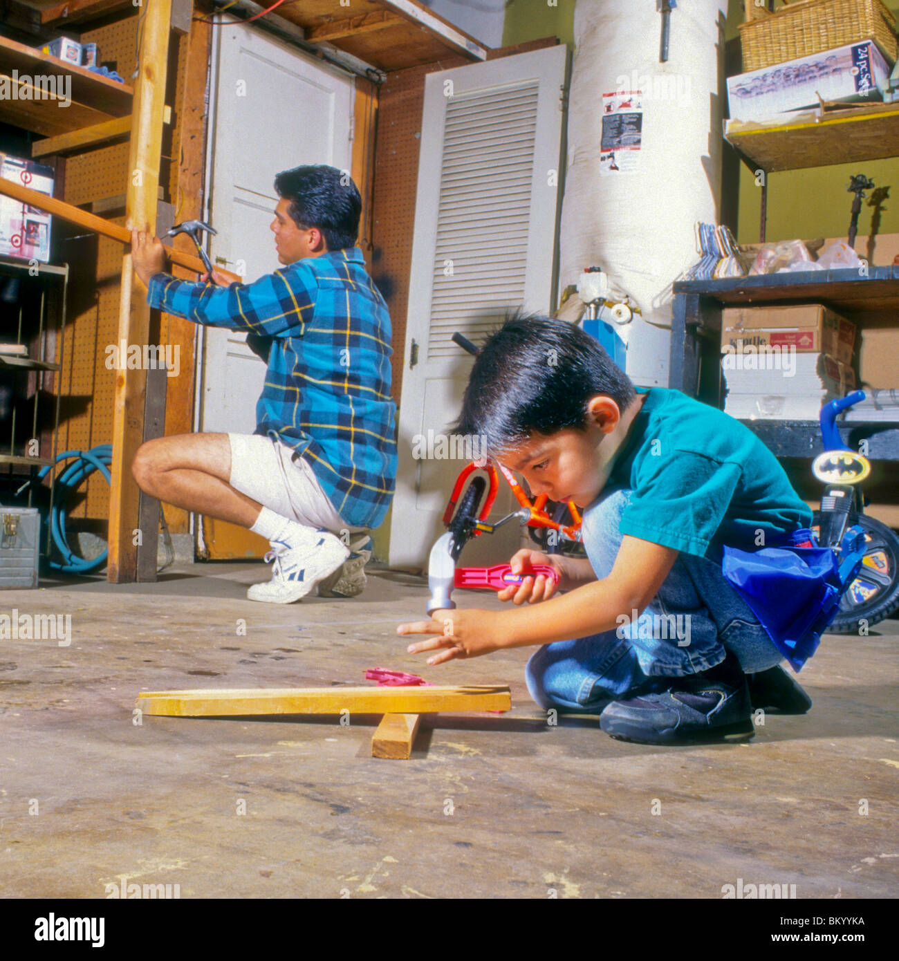 Hispanic son imitates dad father as they work and play together in ...