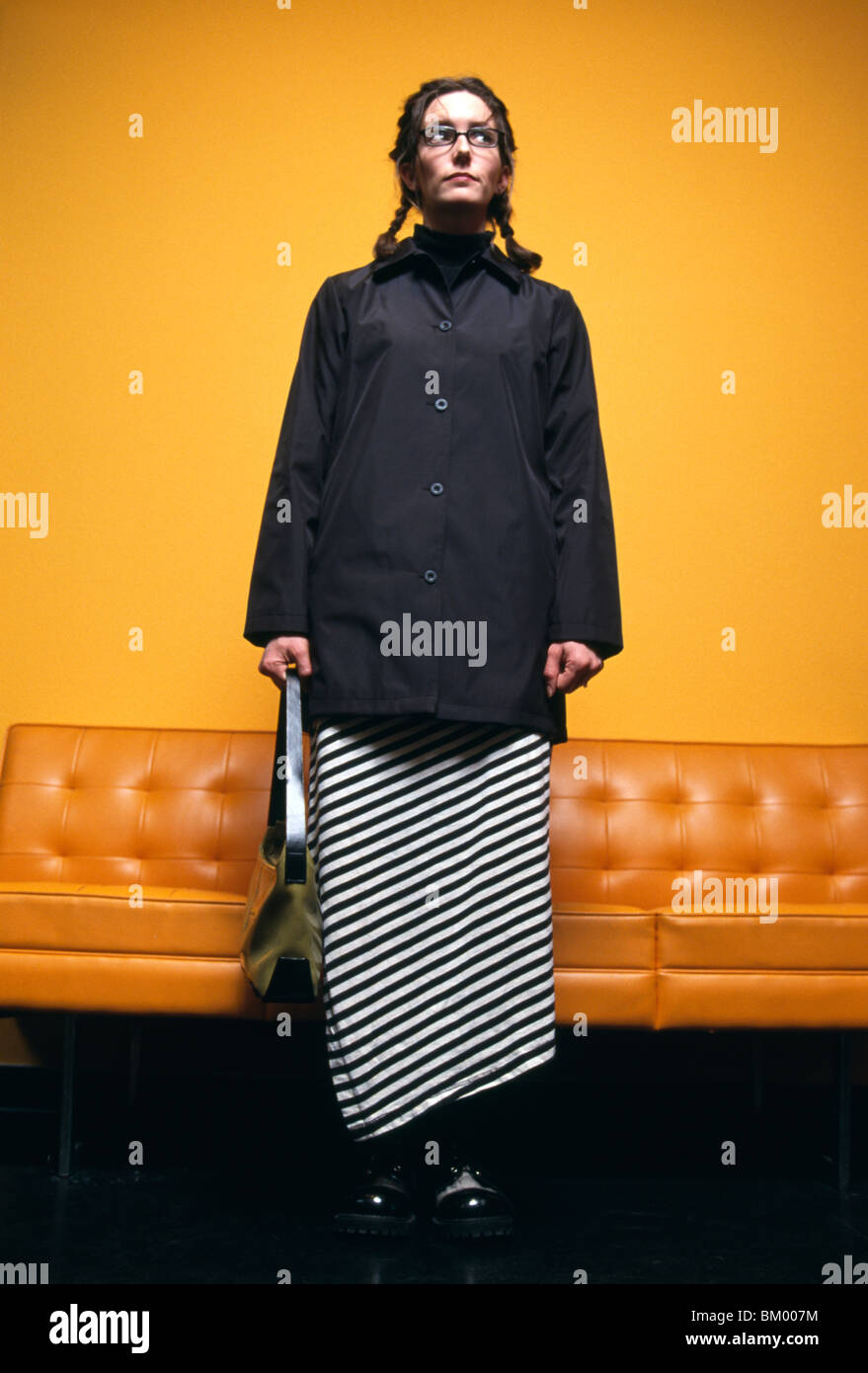Young woman standing in front of couch Stock Photo - Alamy