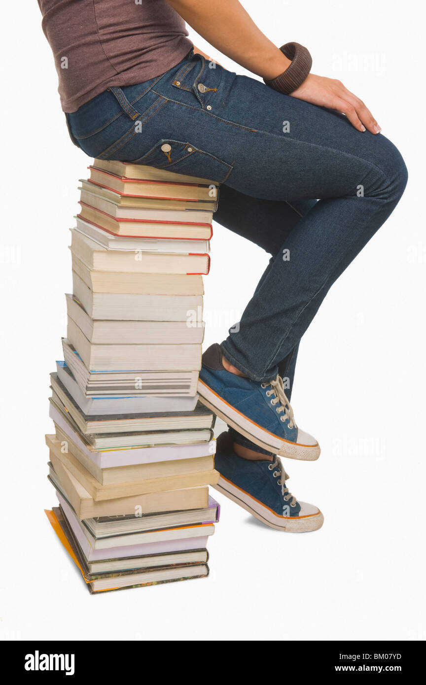 Woman sitting on a stack of books Stock Photo - Alamy