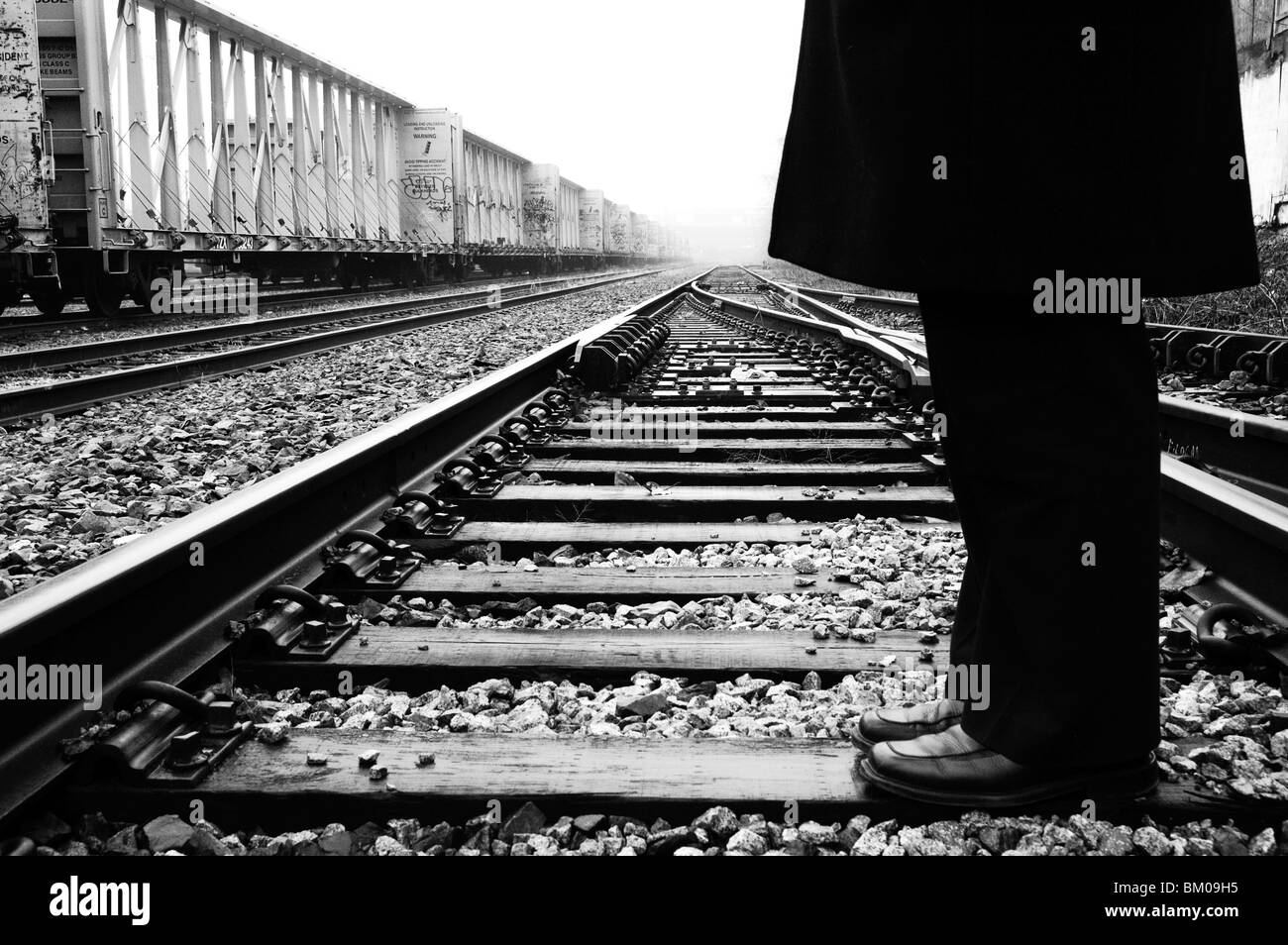 A man wearing dark trousers and coat standing on a railway line Stock ...