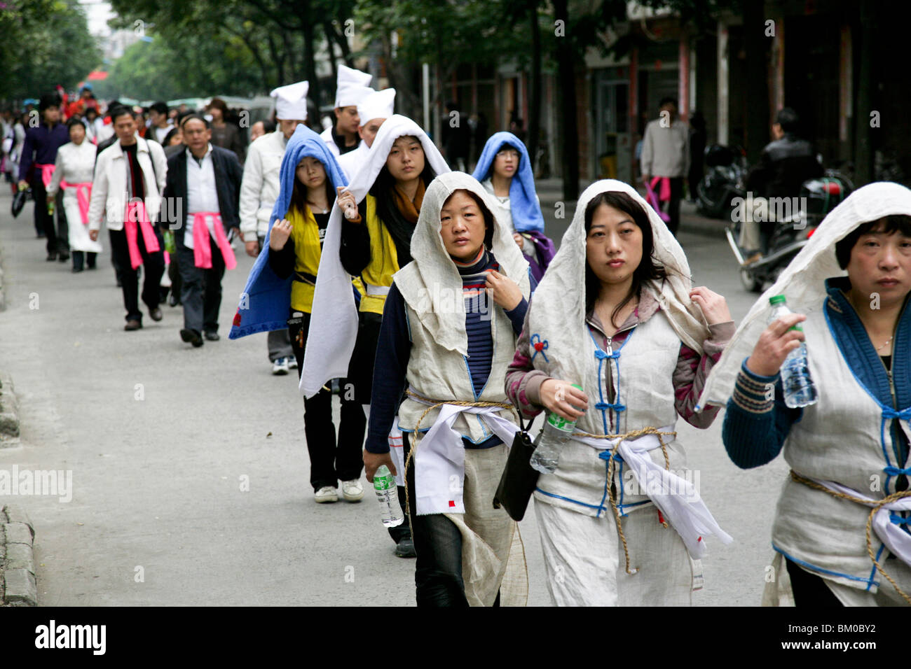 People at a mourning procession on the street, women with white shawls ...