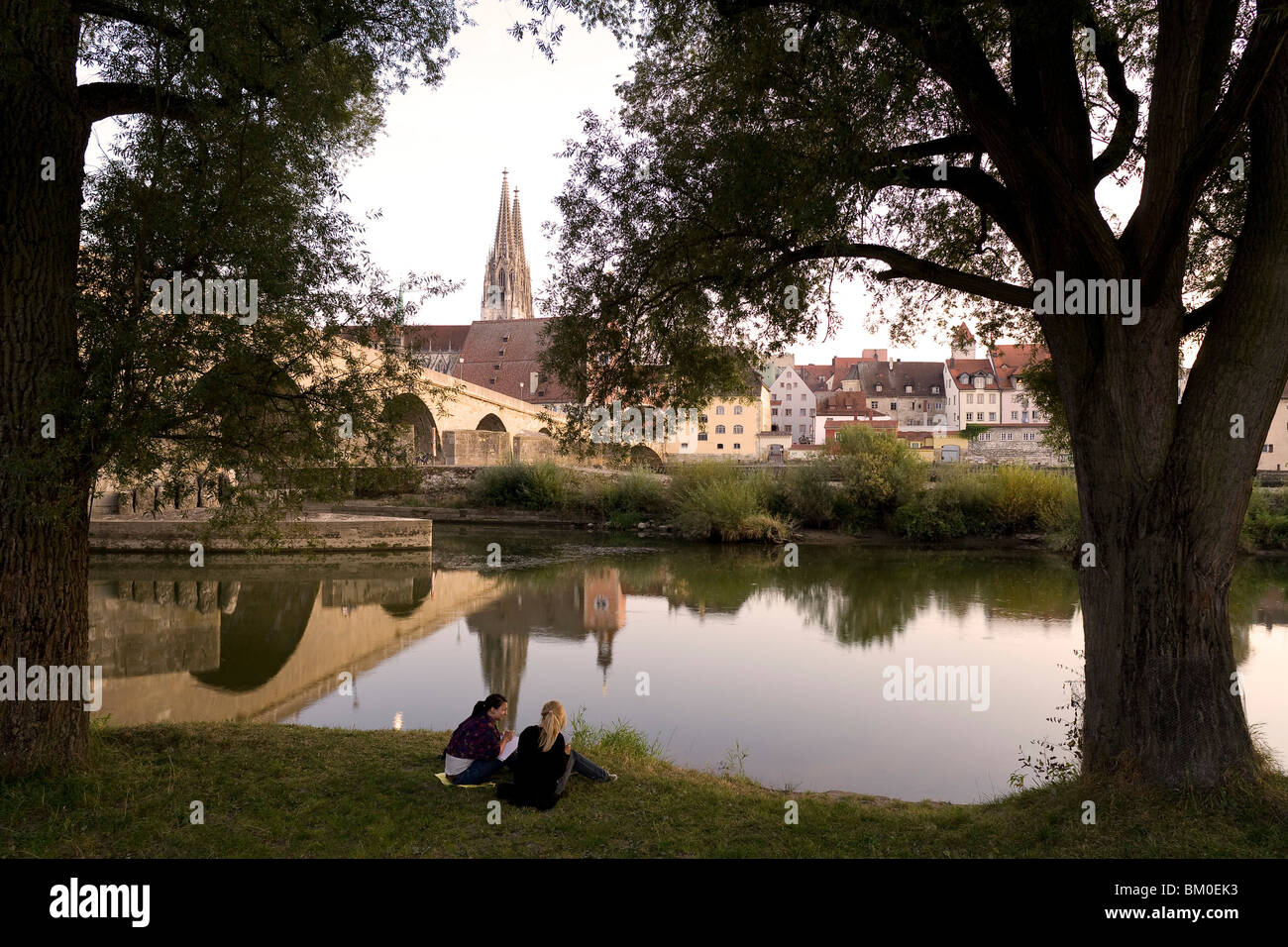 Two young girls sitting on the banks of the river, Stone bridge and ...