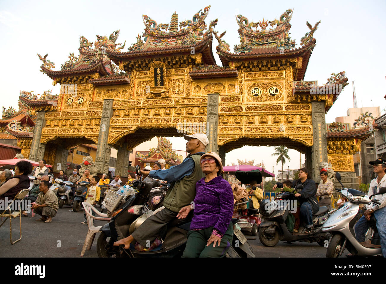 Men and women in front of a splendorous temple gate Pailou, Donggang ...