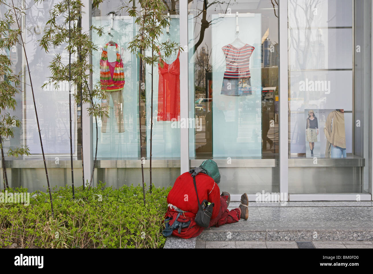 Homeless sits in front of fashion shop window Stock Photo - Alamy