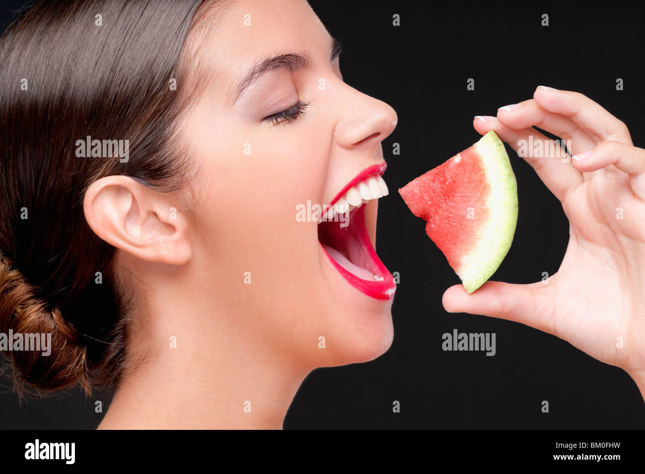 Woman eating a watermelon slice and smiling Stock Photo - Alamy