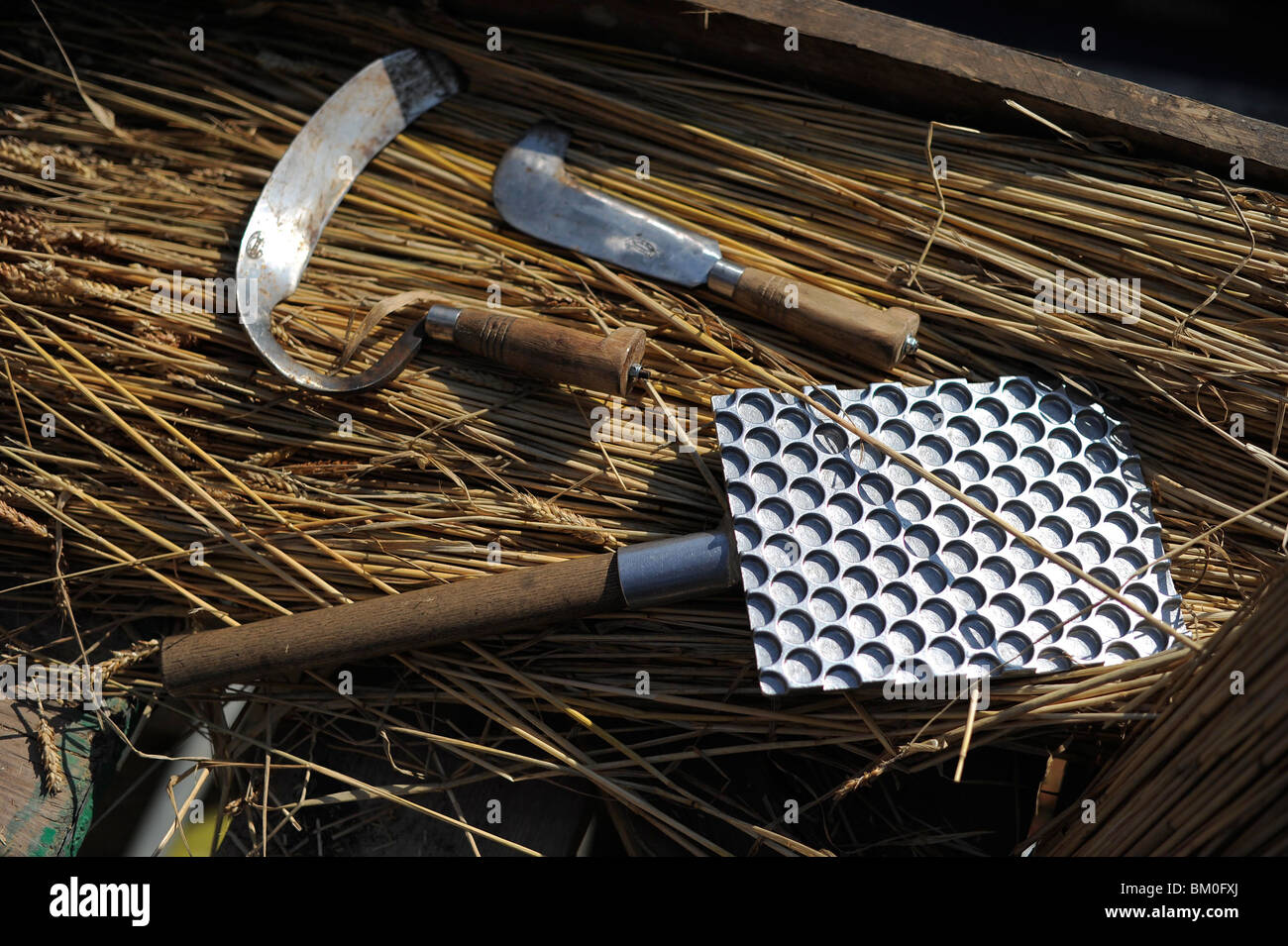 The tools of a master thatcher pictured working on a thatched roof, on ...