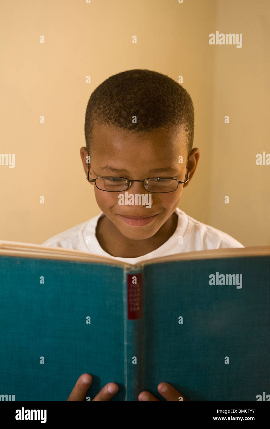 Boy (8-9) smiling while reading book, St Francis Bay, Sea Vista ...