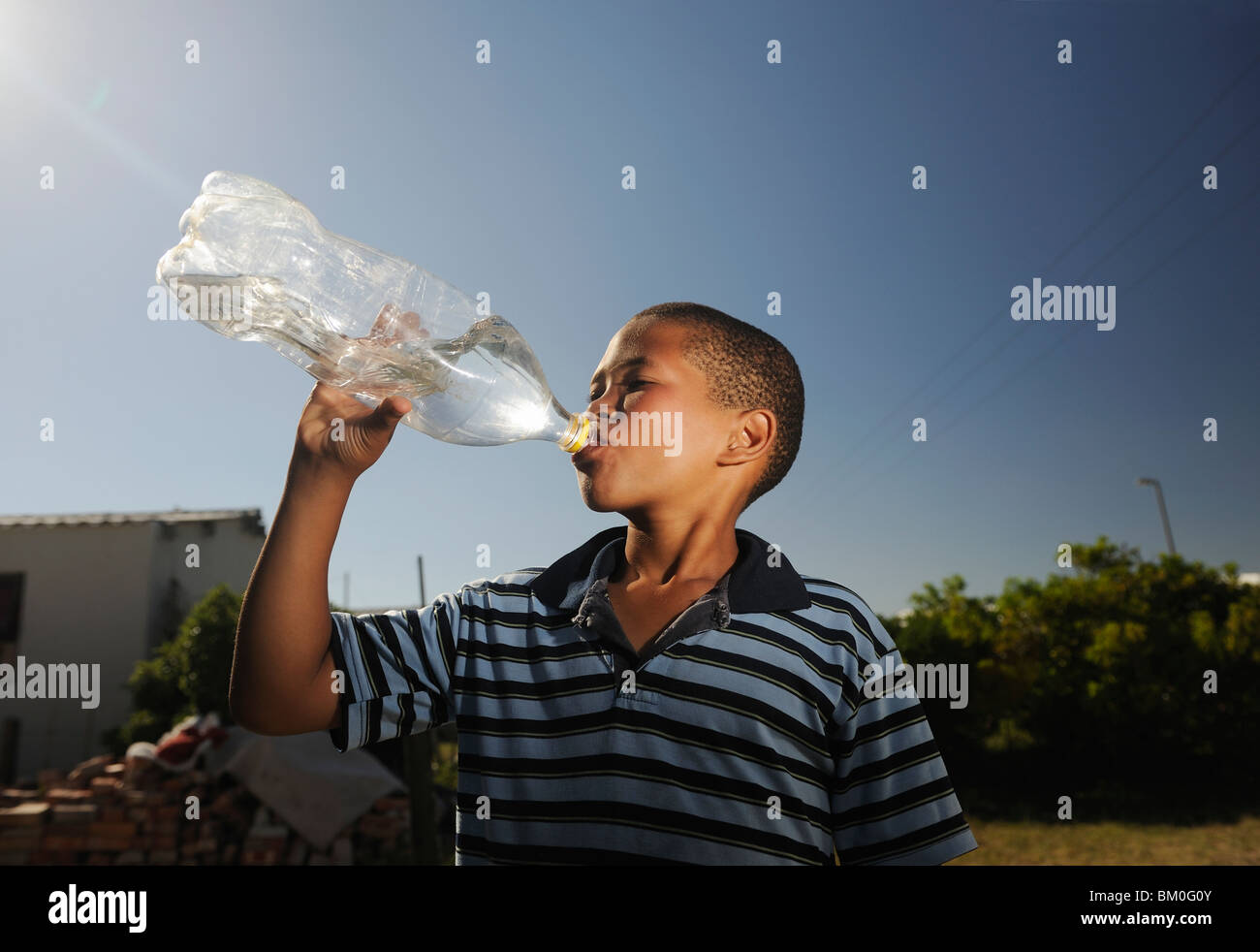 Boy (12-13) drinking water from plastic bottle, St Francis Bay, Sea ...
