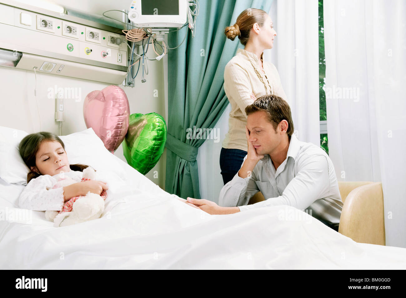 Girl on a hospital bed with her parents beside her Stock Photo - Alamy