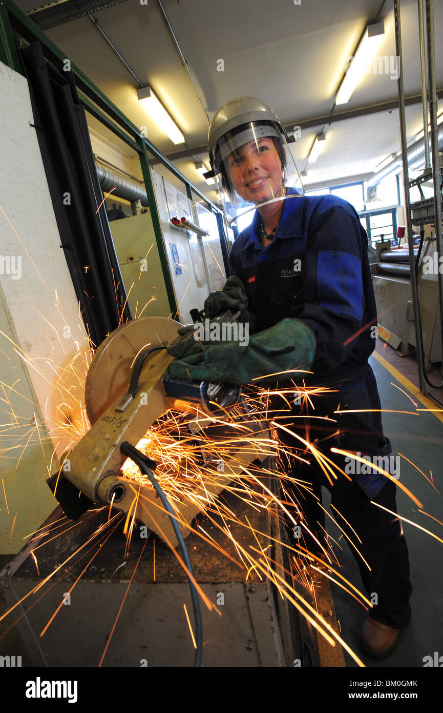 a female engineering student using an angle grinder, creating sparks in ...