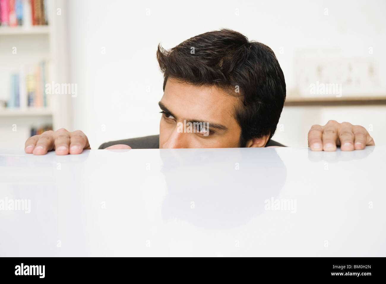 Businessman watching from behind a table Stock Photo - Alamy
