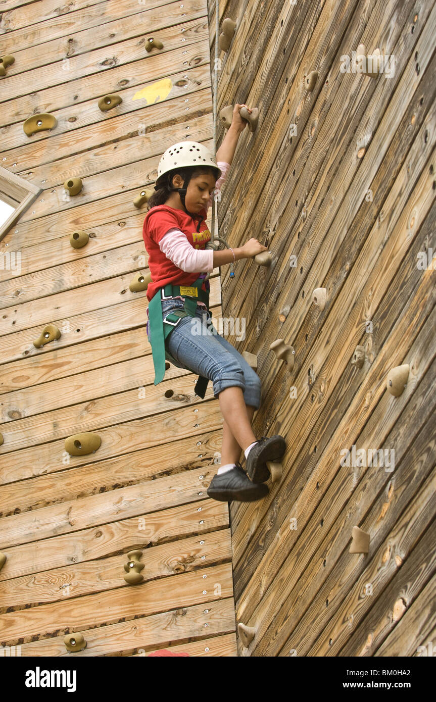 Middle school girl in safety gear scales climbing wall at outdoor ...