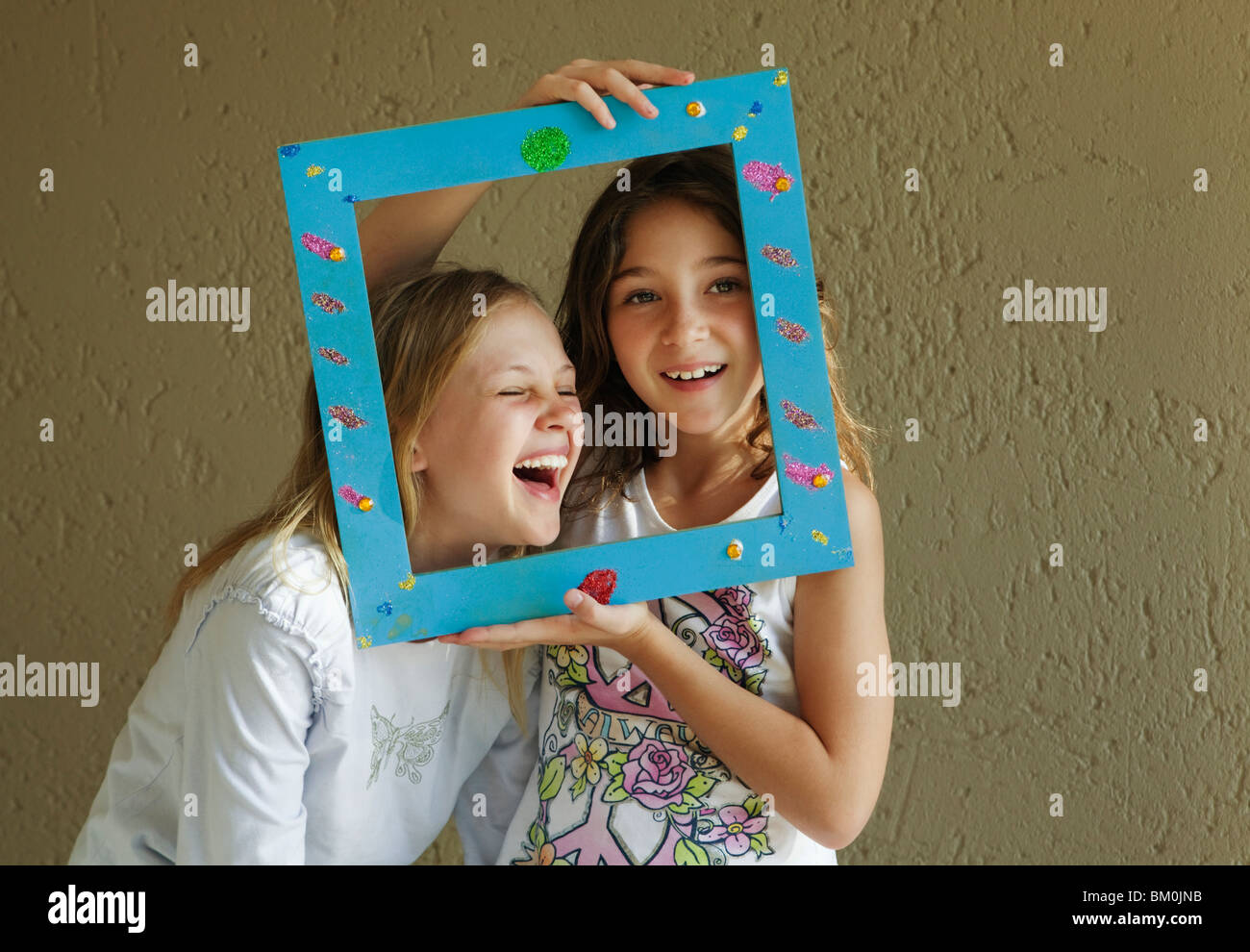 Girls looking through picture frame Stock Photo - Alamy