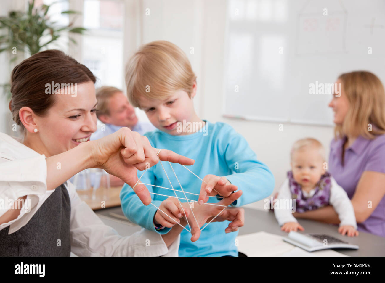 Businesswoman, boy playing string game Stock Photo - Alamy