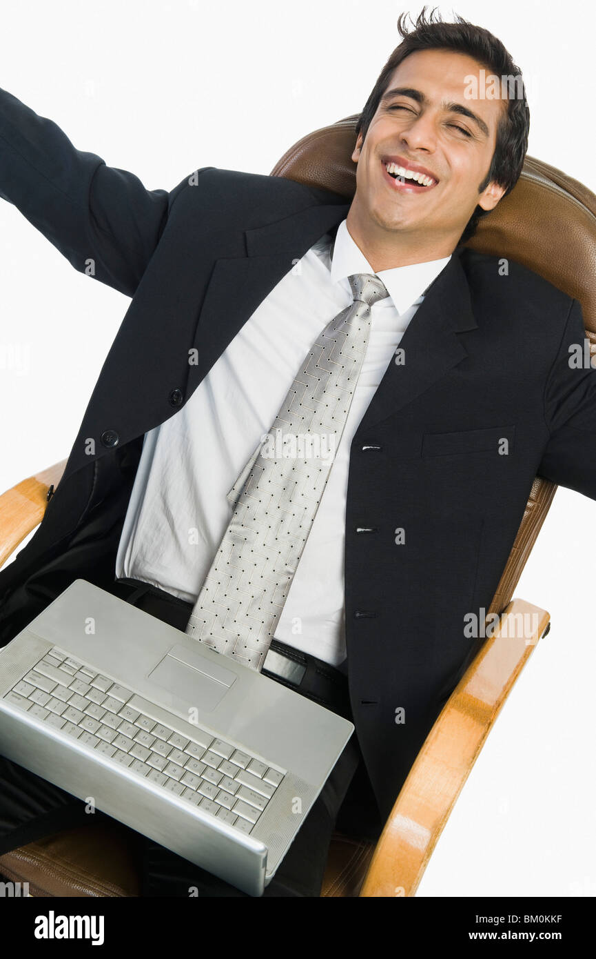 Businessman sitting on a chair with a laptop Stock Photo - Alamy