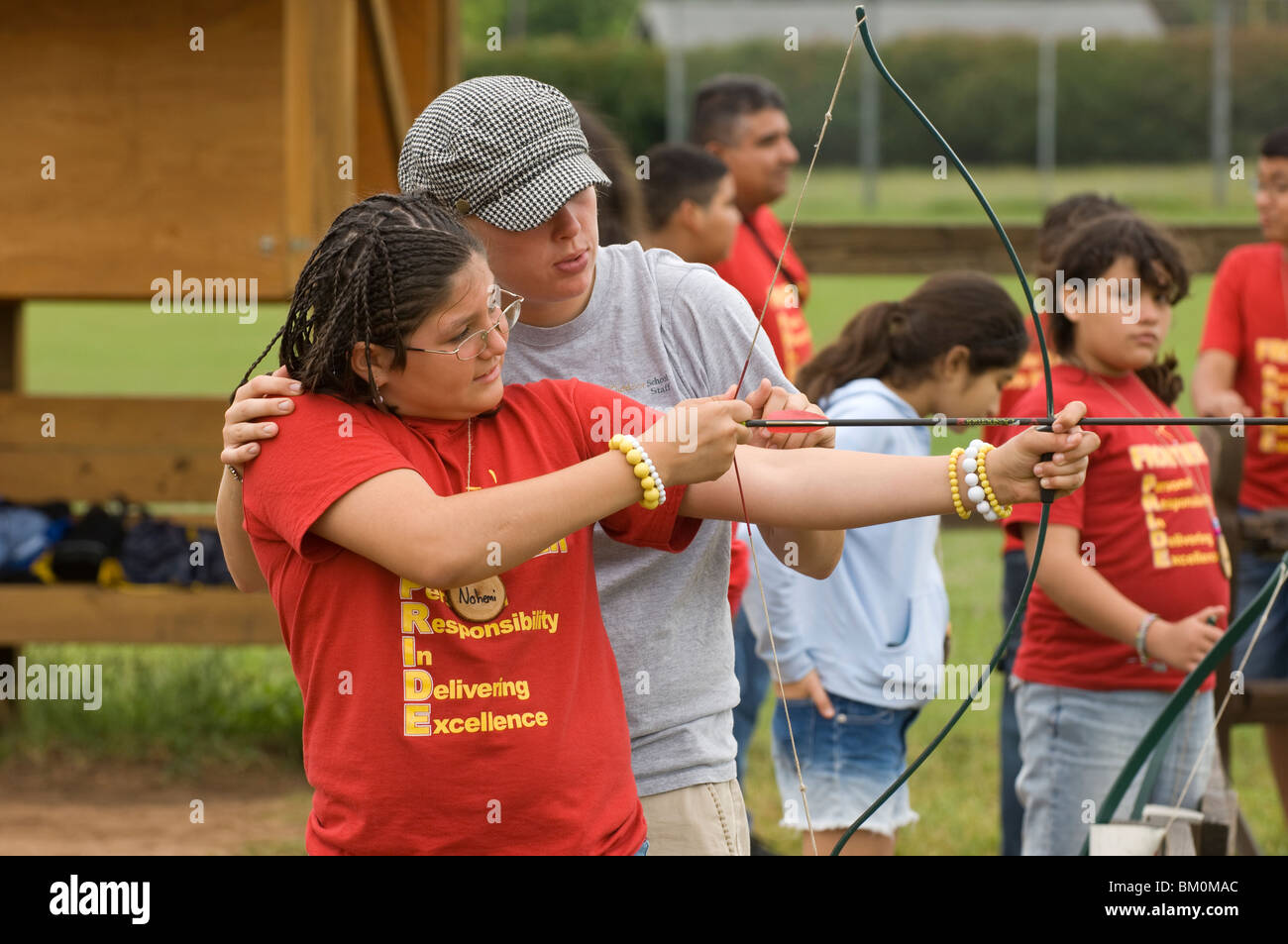 Hispanic middle school girl uses bow and arrow during archery lesson at ...