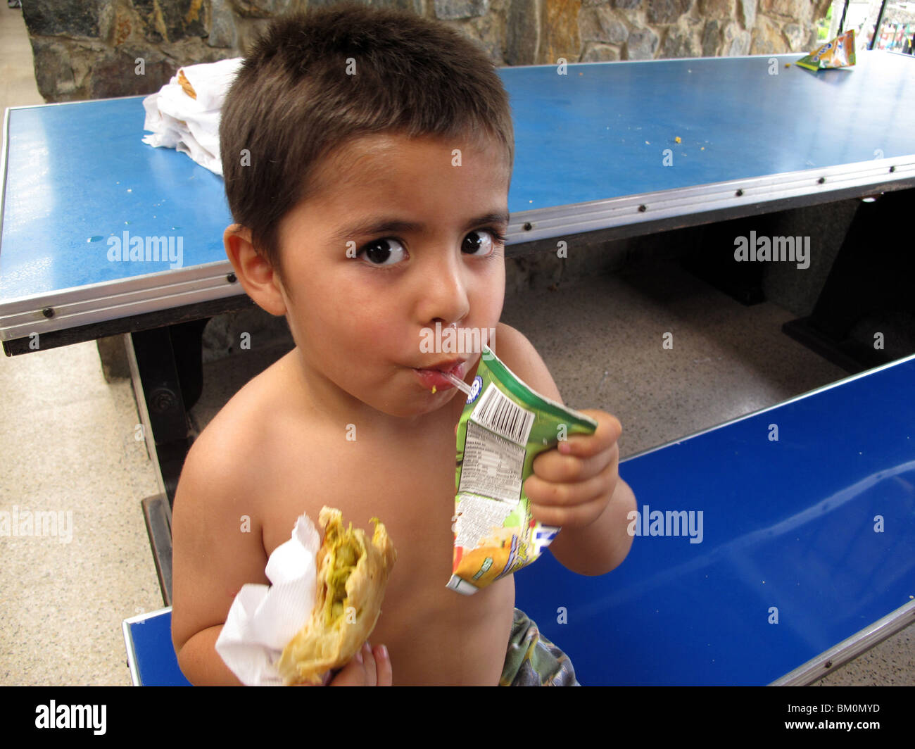 Boy 3 years drinking and eating on blue bench. Medellin Stock Photo - Alamy