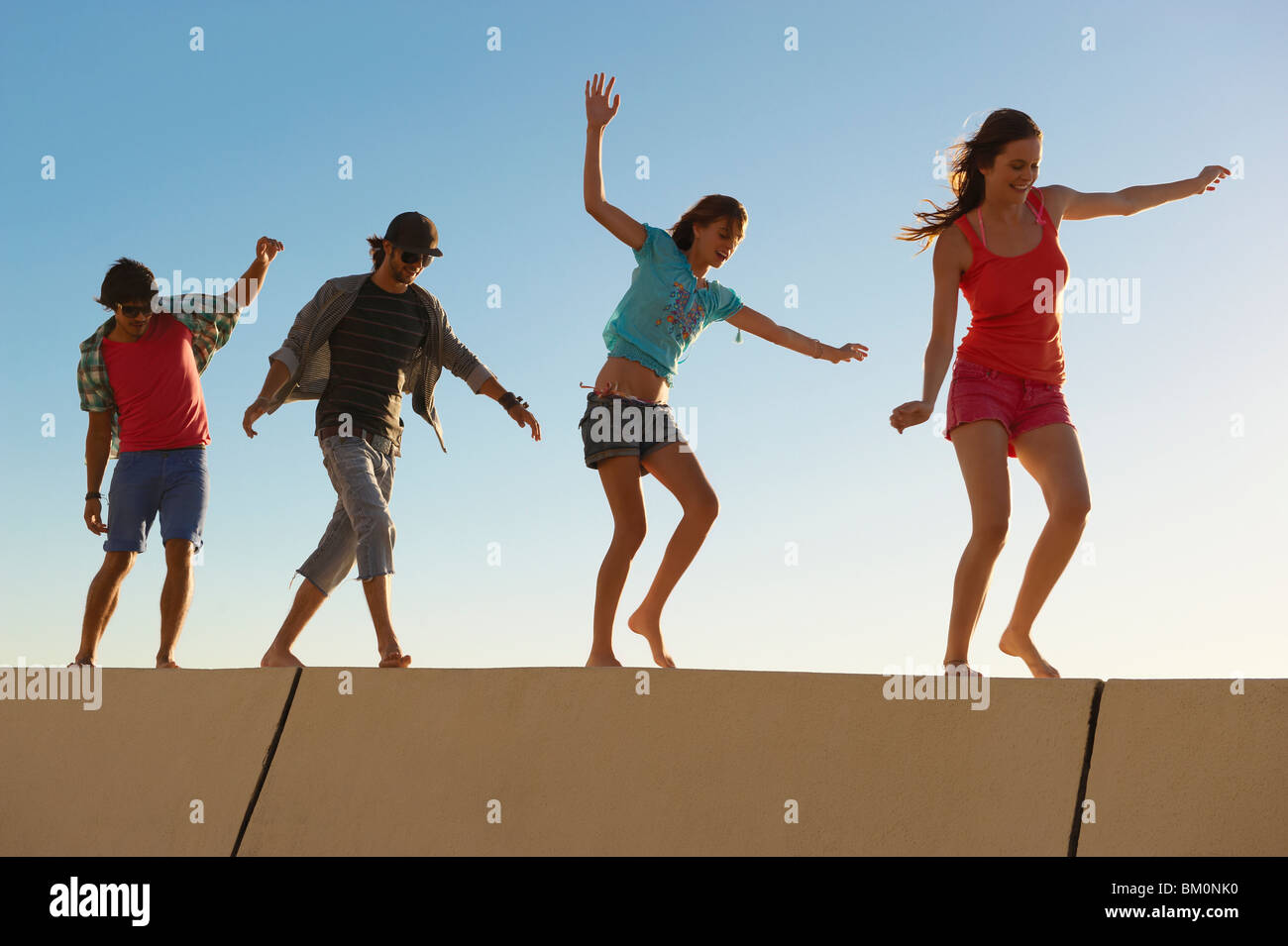 Young people balancing on wall Stock Photo - Alamy