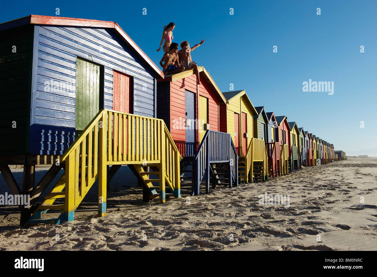 Young people sitting on top of beach hut Stock Photo - Alamy