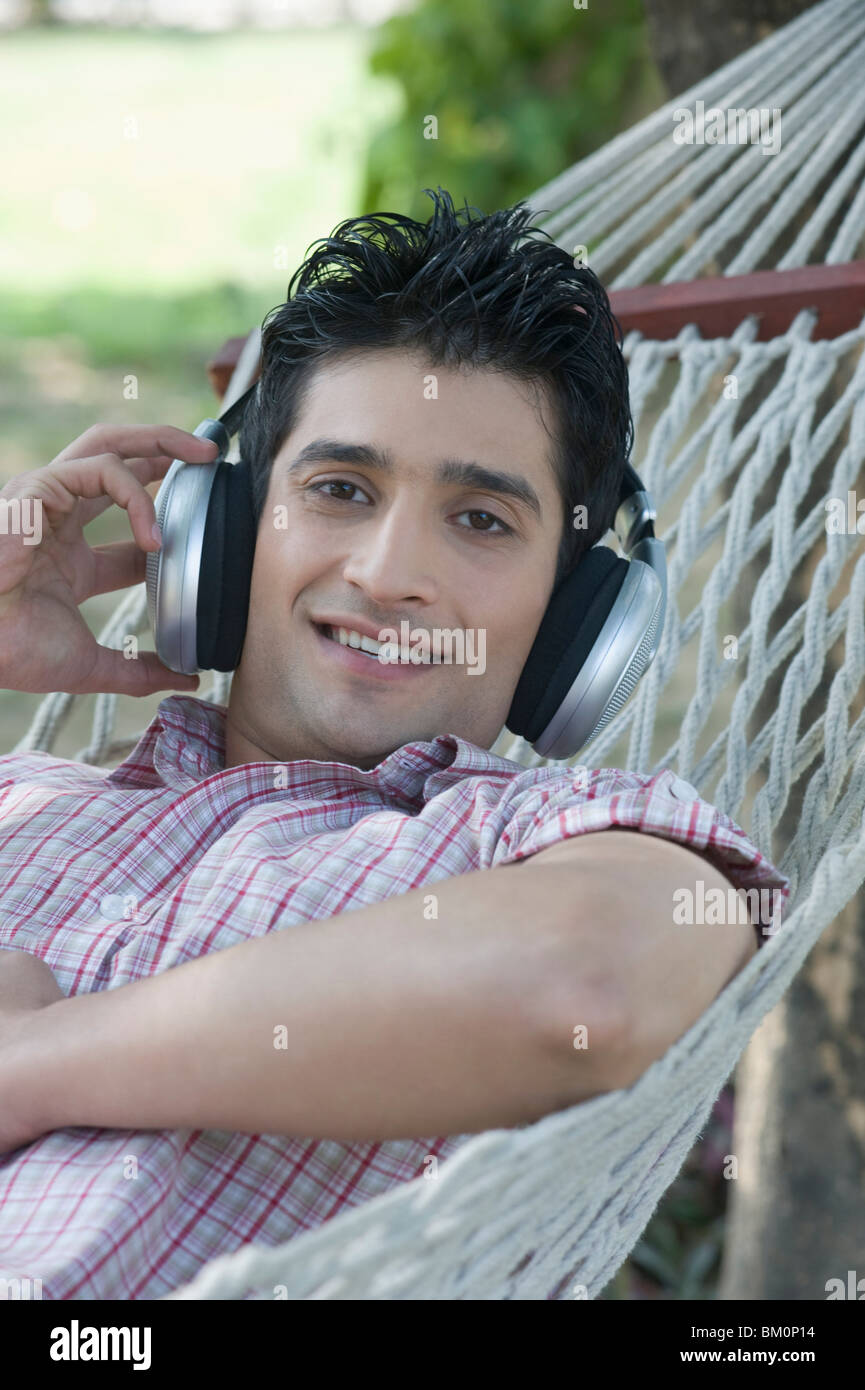 Man lying in a hammock and listening to music Stock Photo - Alamy
