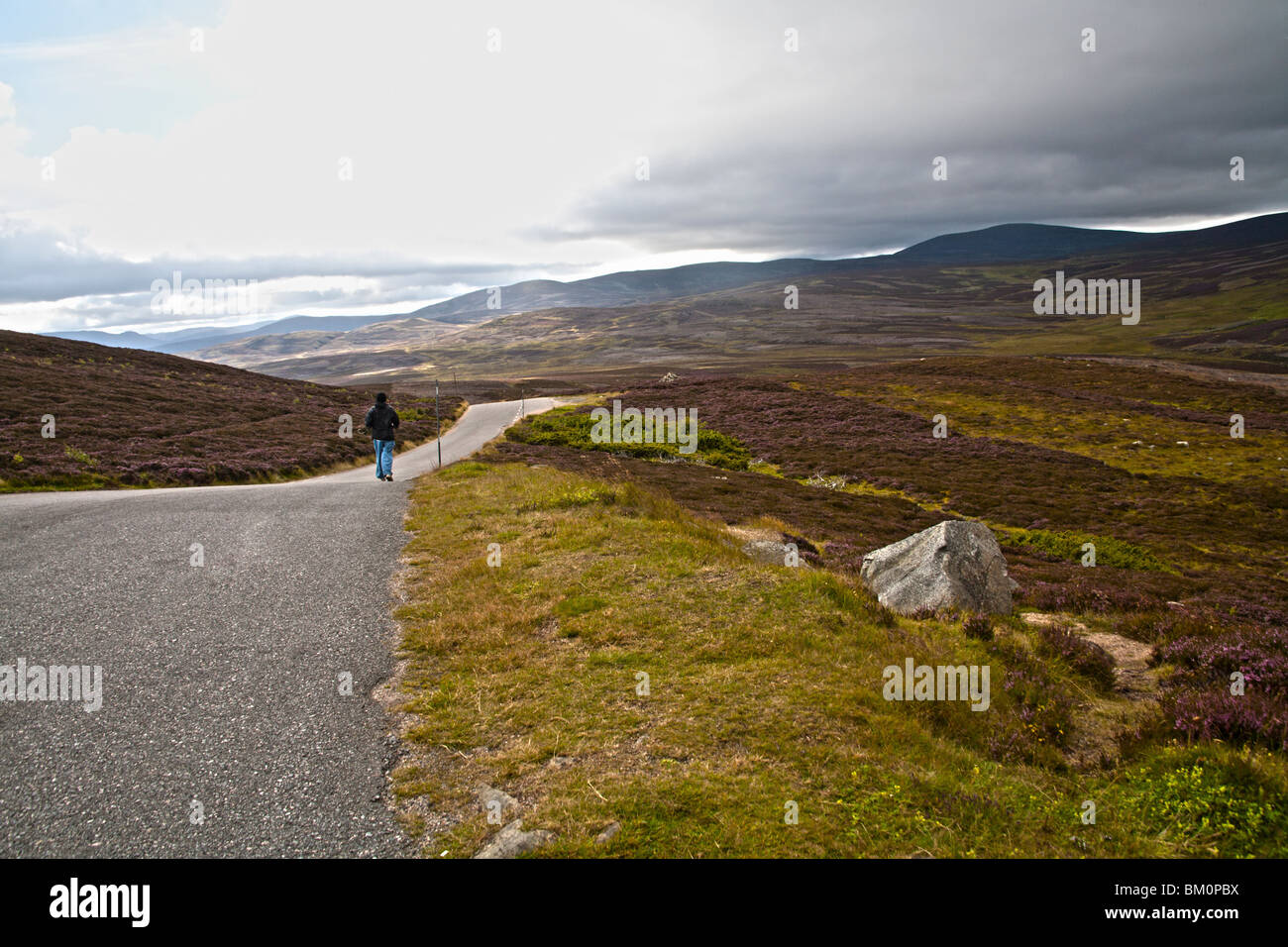 A lone man walking on a desolate road. Grampian Highlands, Scotland ...