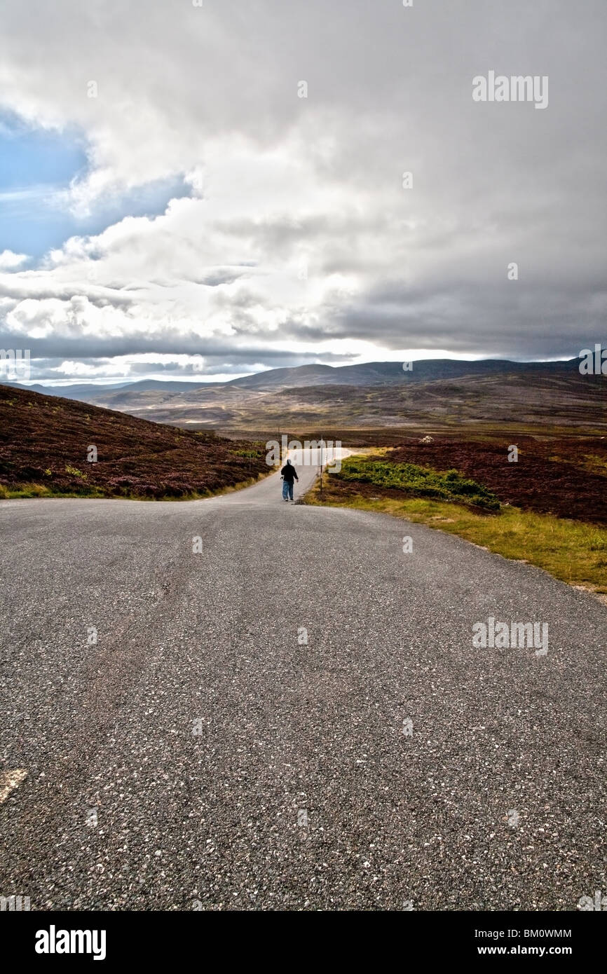 A lone man walking on a desolate road. Grampian Highlands, Scotland ...