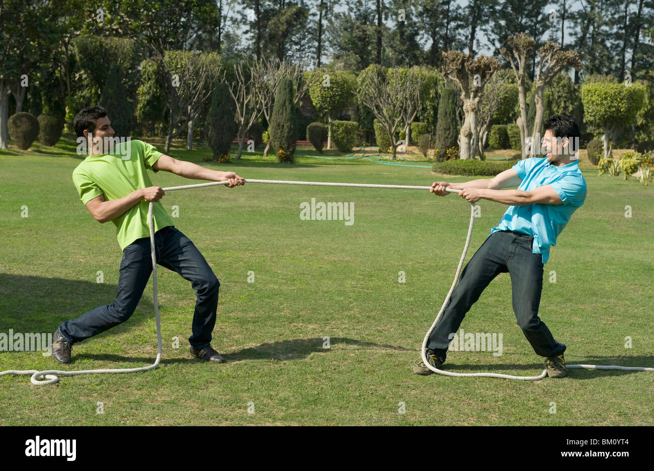 Two friends pulling rope in a park Stock Photo - Alamy