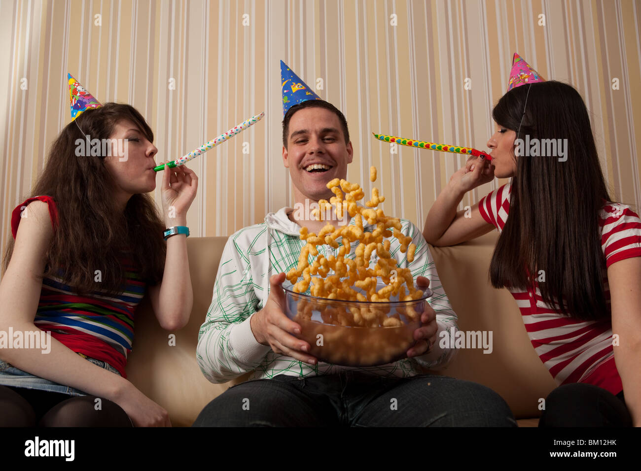 Three friends sitting on the couch in the living room and partying ...