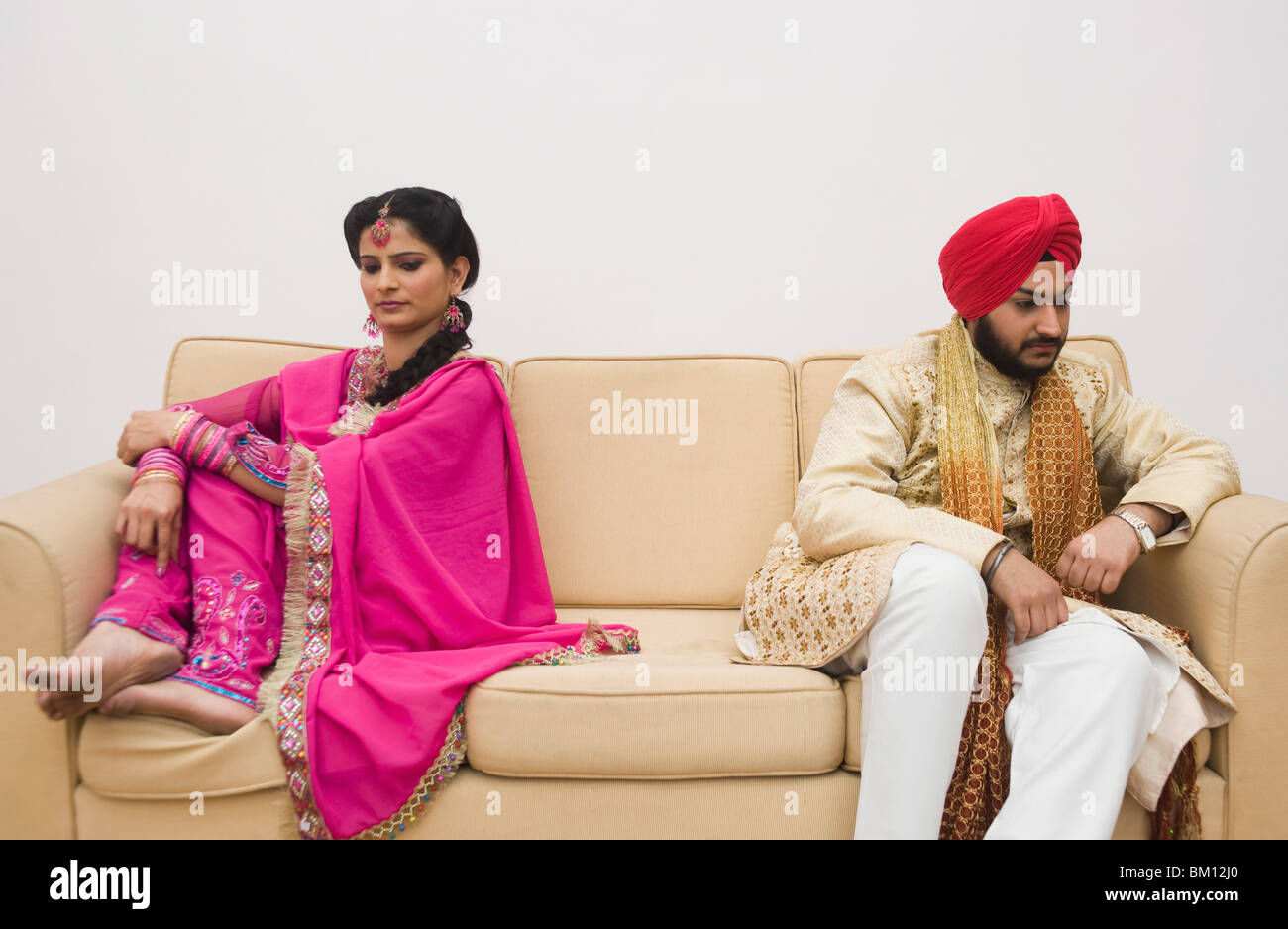 Sikh couple sitting on a couch and looking sad Stock Photo - Alamy