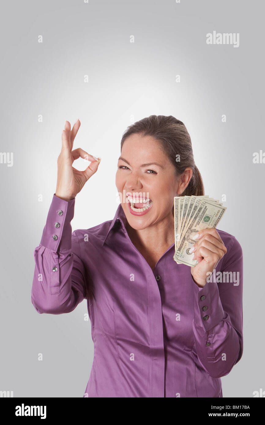 Woman holding currency notes and showing OK sign Stock Photo - Alamy