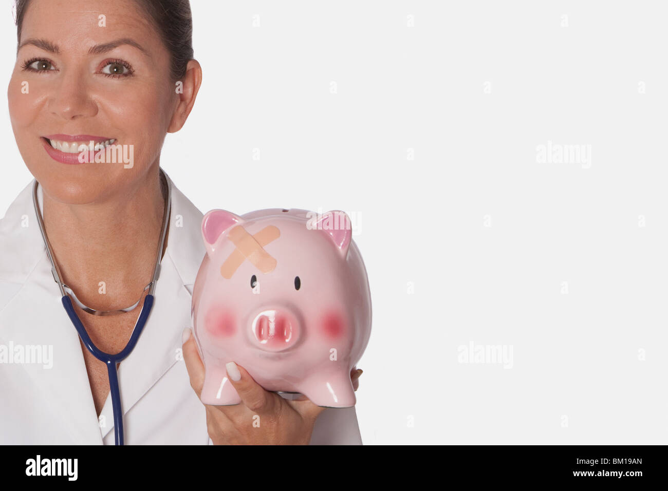 Female doctor holding a piggy bank Stock Photo - Alamy