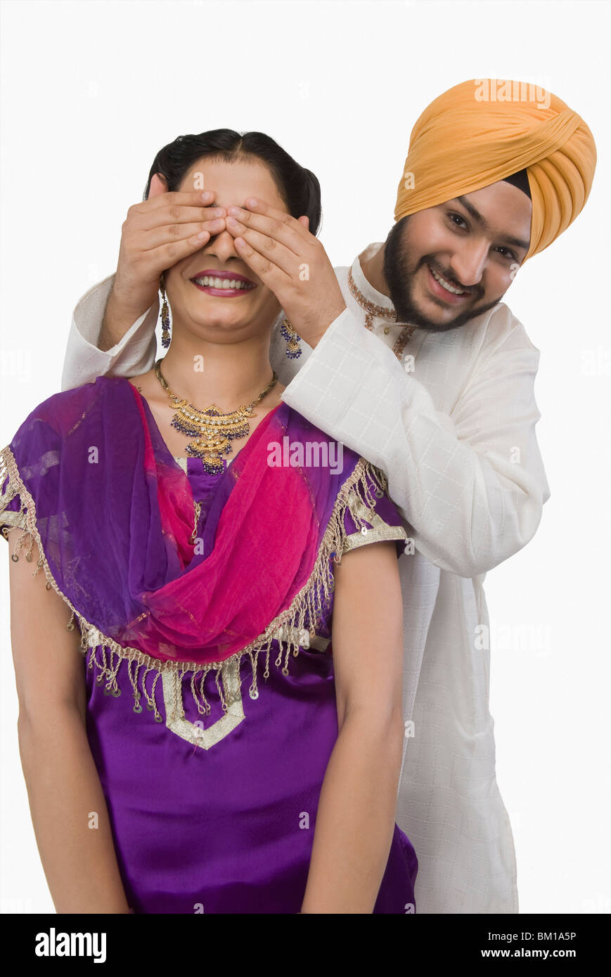 Sikh man covering a woman's eyes from behind Stock Photo - Alamy