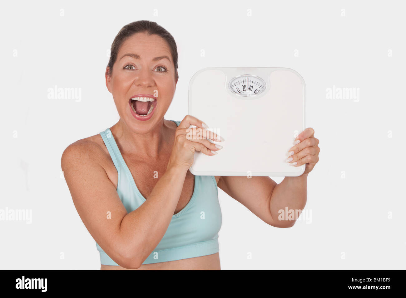 Portrait of a woman holding a bathroom scale and laughing Stock Photo ...