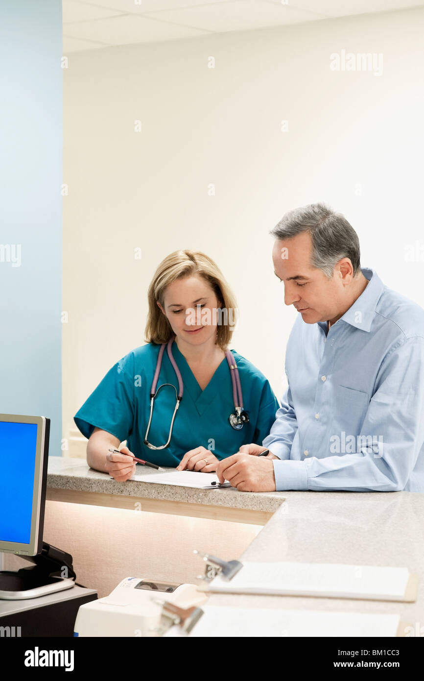 Female doctor examining a report with a patient standing beside her at ...