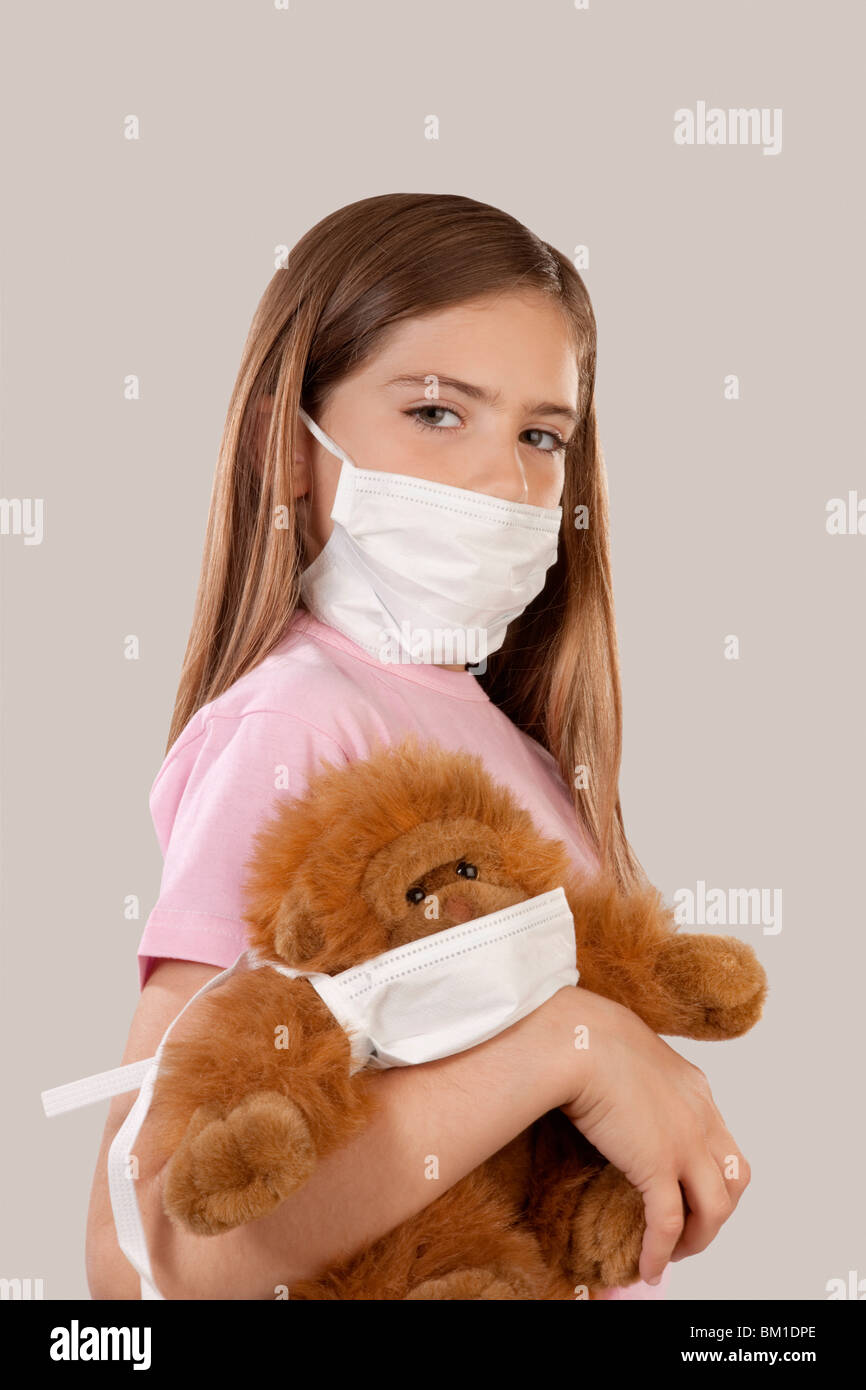 Girl wearing flu mask and holding a teddy bear Stock Photo - Alamy