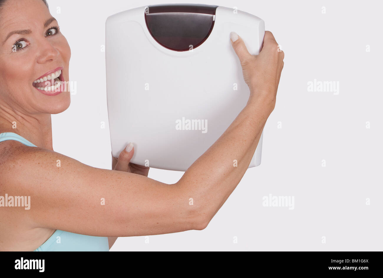 Portrait of a woman holding a bathroom scale and laughing Stock Photo ...
