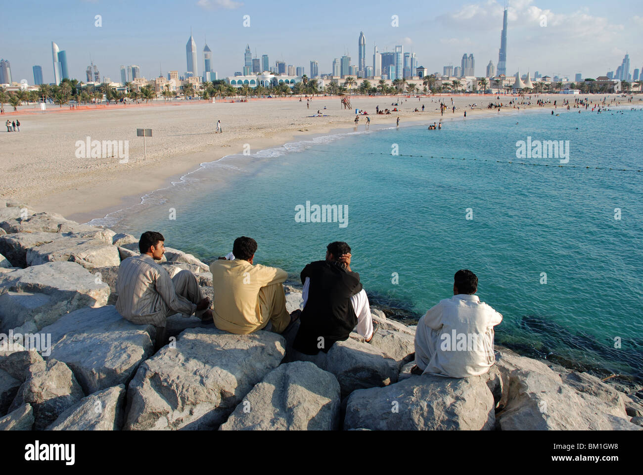 Men sitting on rocks watching Dubai's Jumeira beach. UAE Stock Photo ...