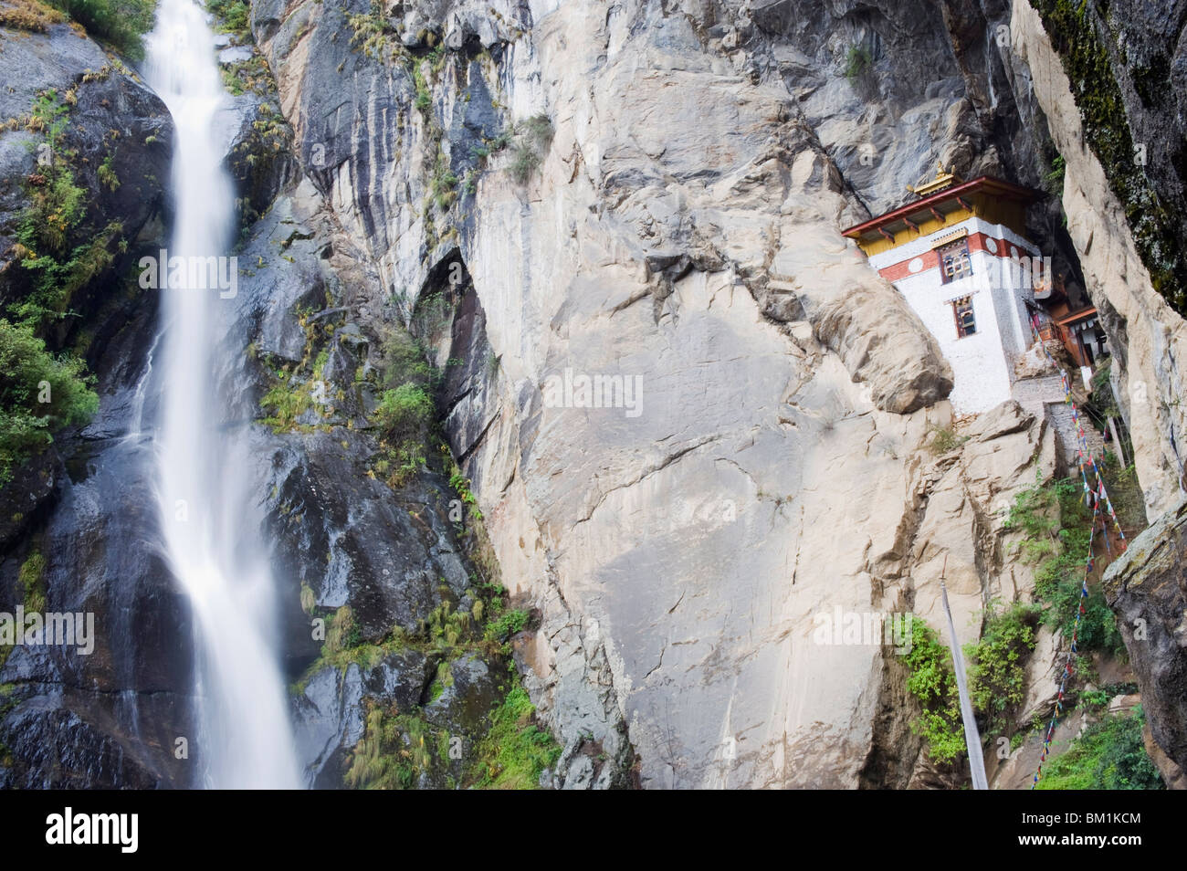 A waterfall flowing past a temple built into the side of a cliff ...