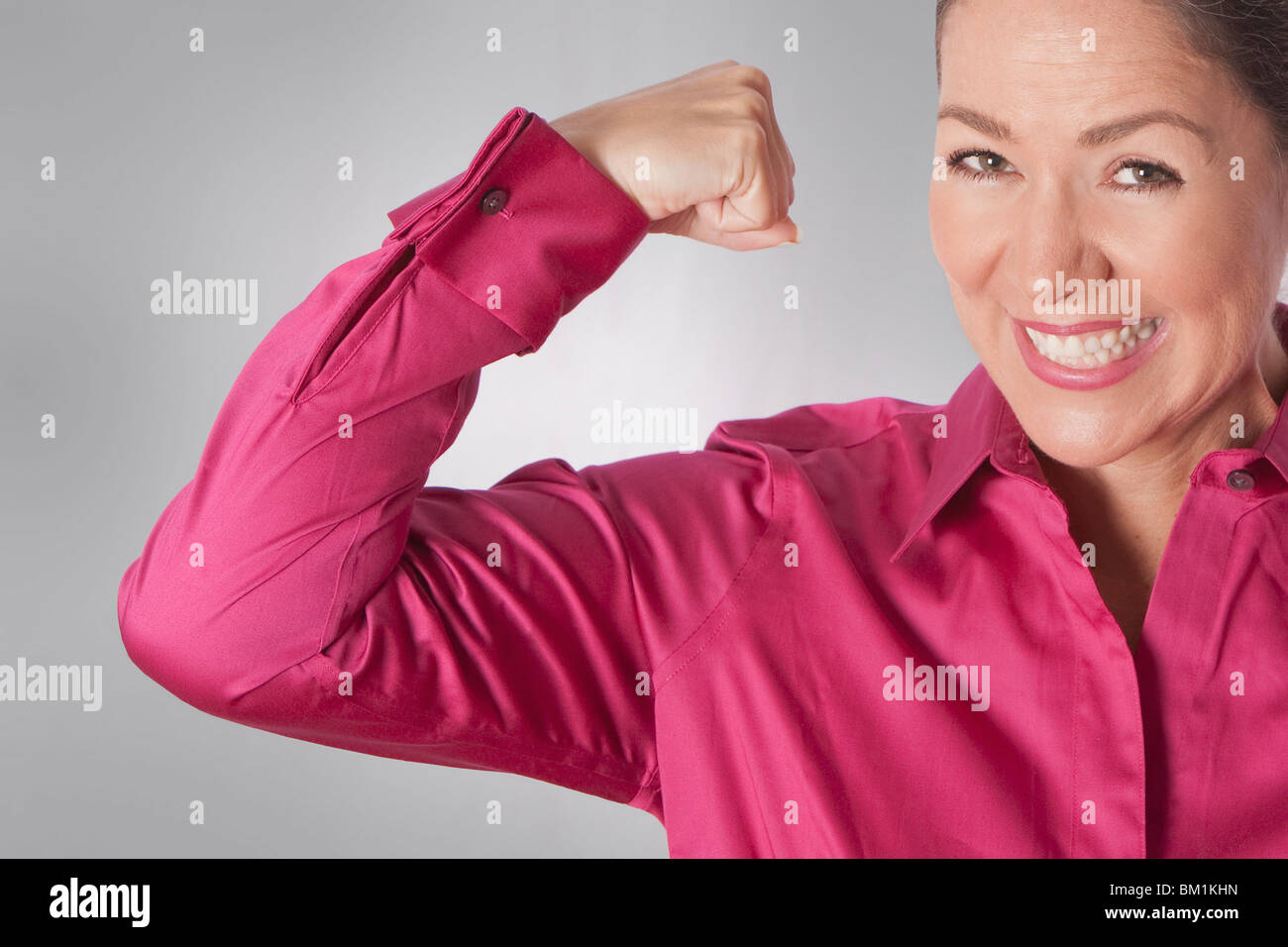 Portrait of a woman flexing her muscles and smiling Stock Photo - Alamy