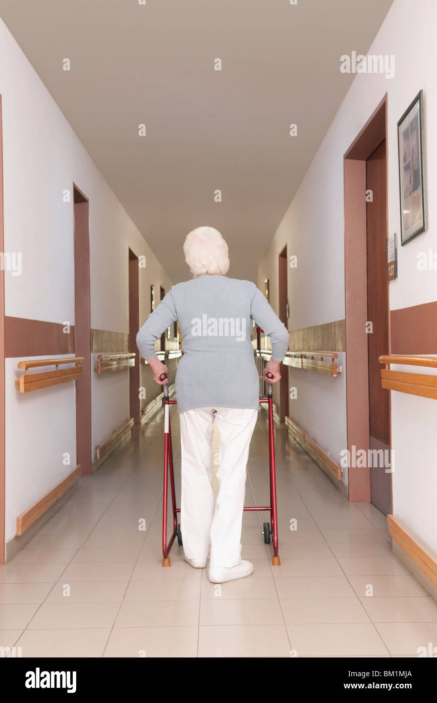 Rear view of a woman walking with the help of walker Stock Photo - Alamy