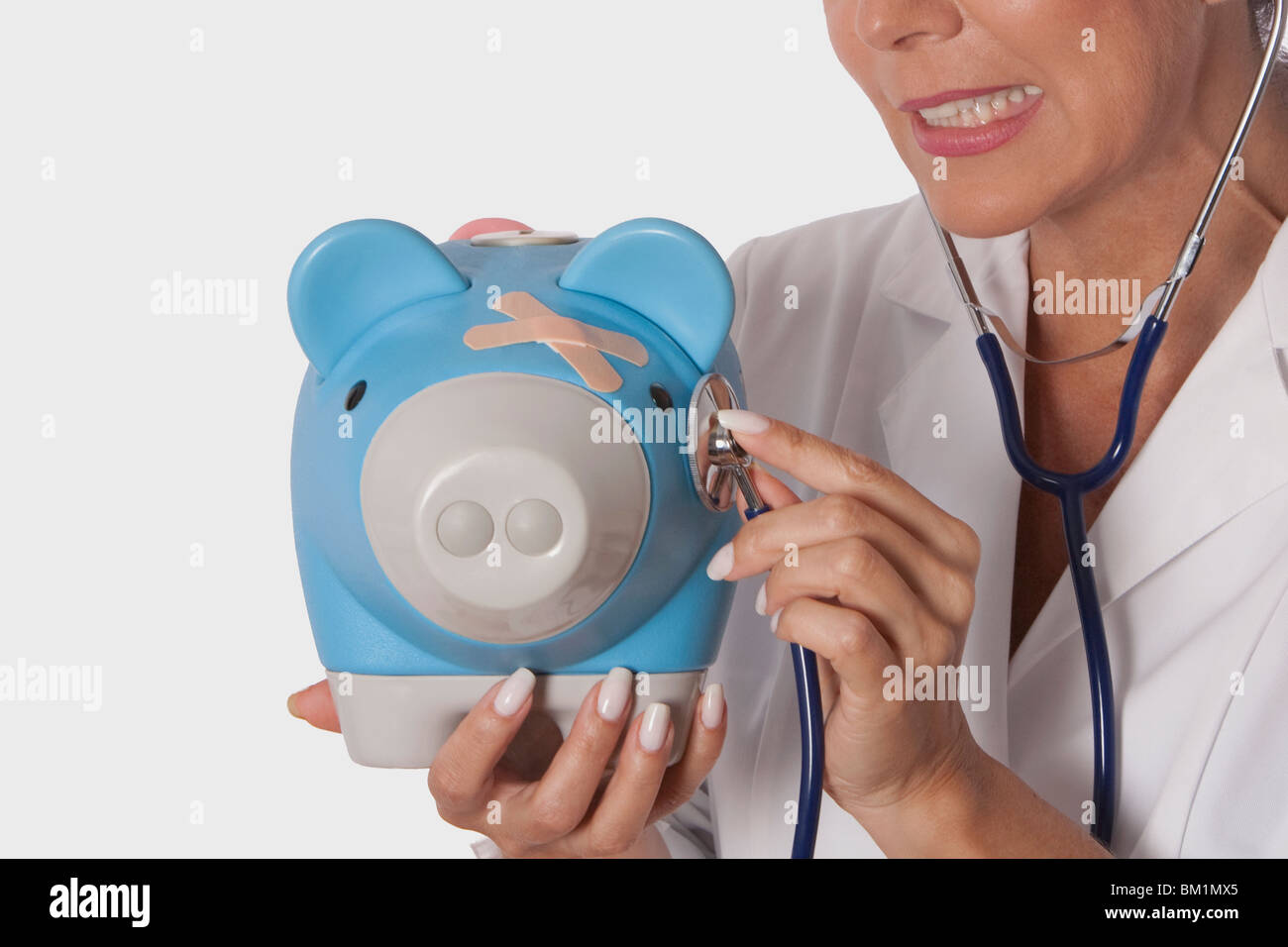 Female doctor examining a piggy bank with a stethoscope Stock Photo - Alamy