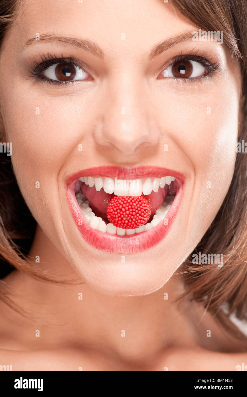 Portrait of a woman holding a raspberry in her mouth Stock Photo - Alamy