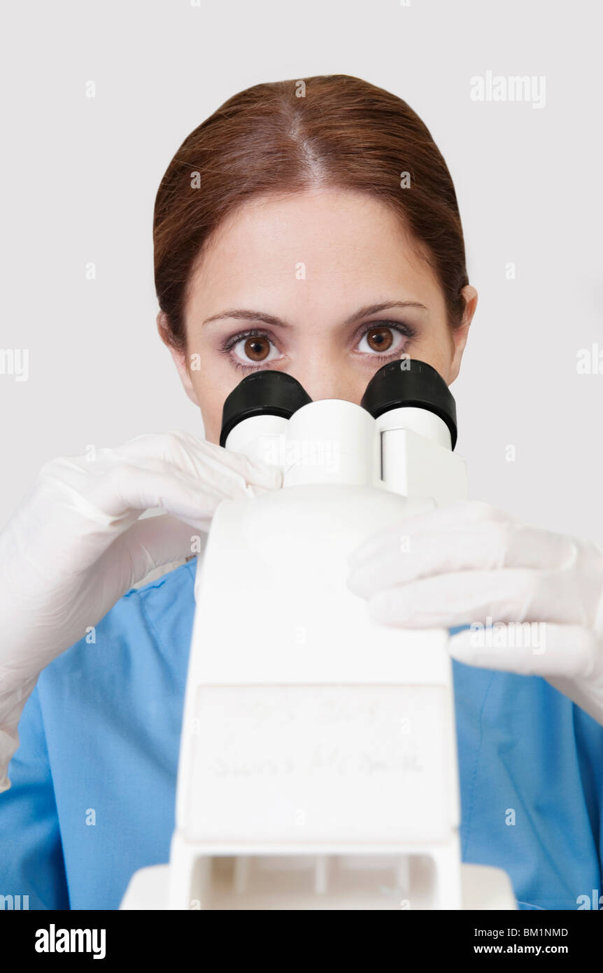 Female lab technician analyzing a sample through a microscope Stock ...