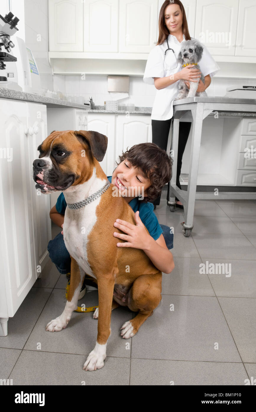 Boy hugging a dog with a vet in the background Stock Photo - Alamy