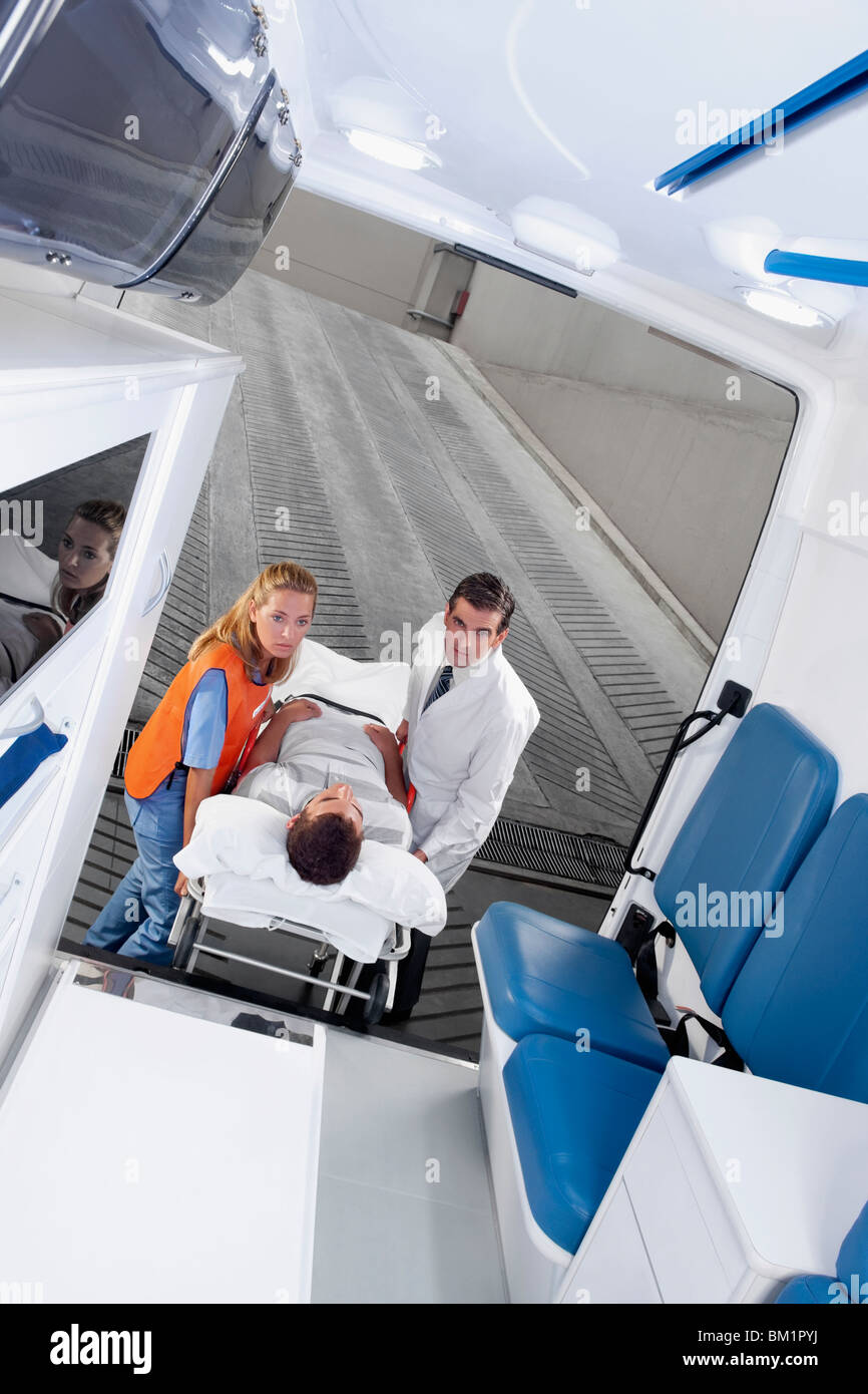 Paramedics leading a patient on a gurney into an ambulance Stock Photo ...