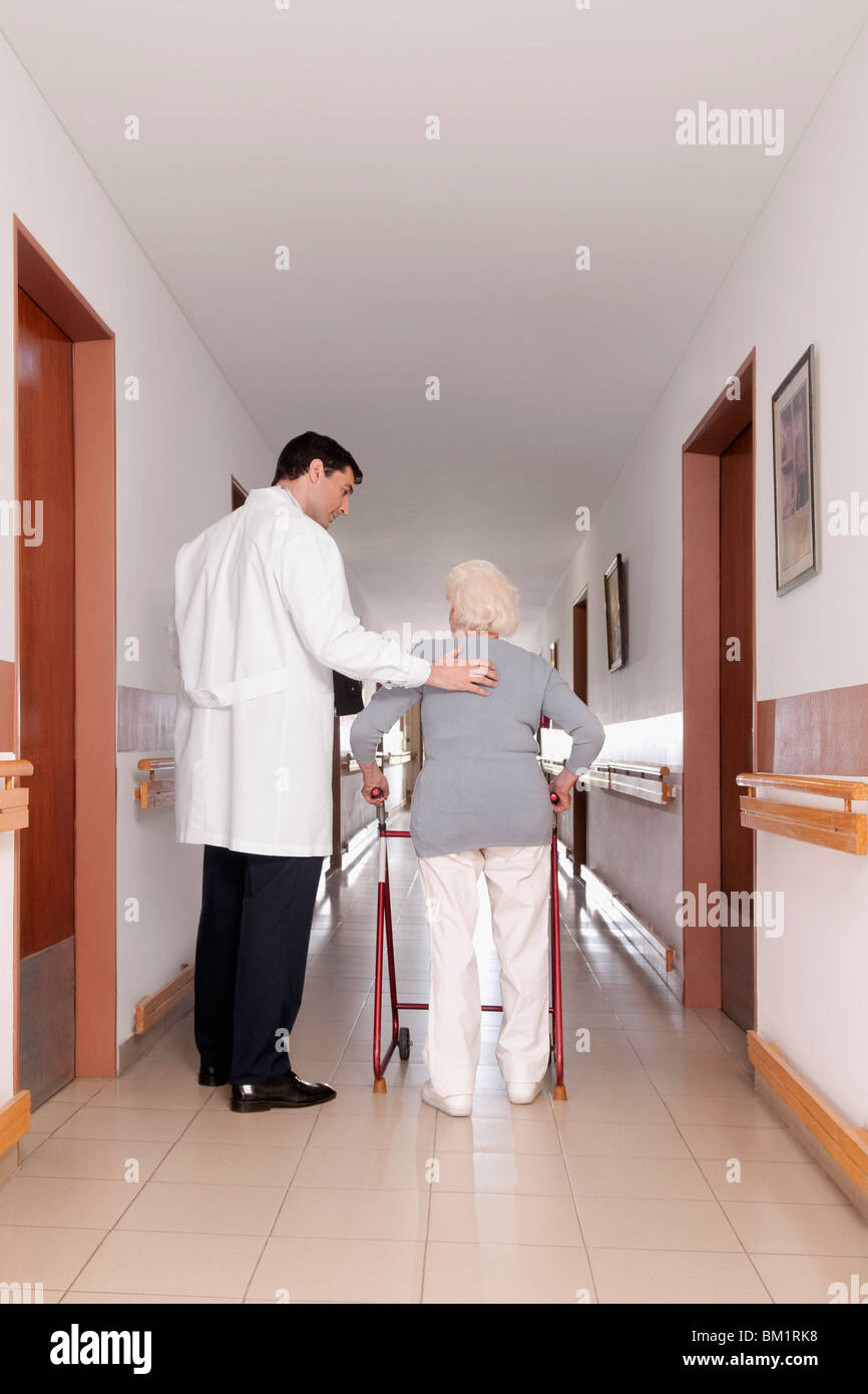 Doctor assisting a woman in walking Stock Photo - Alamy