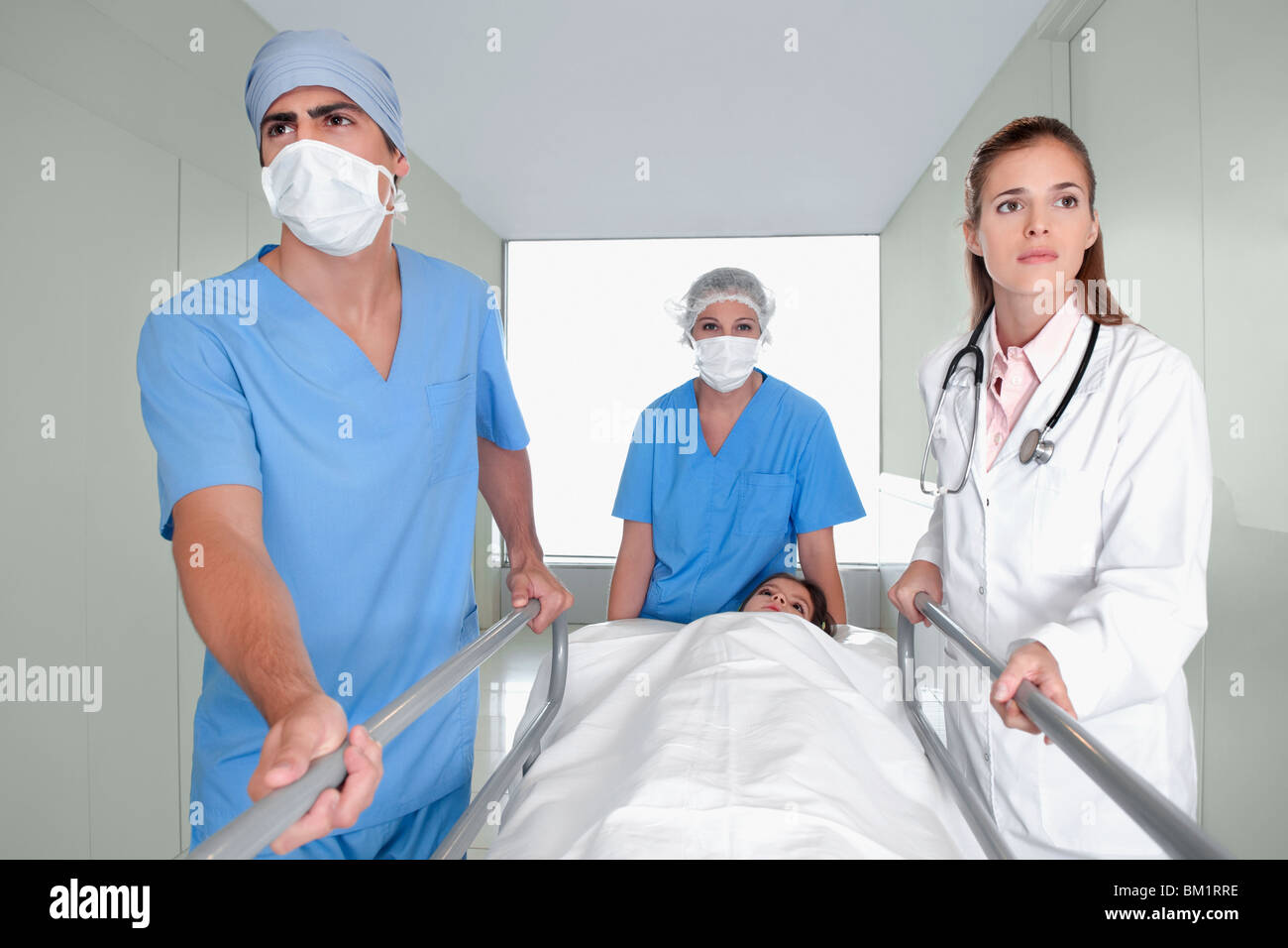 Doctors pushing a patient on a hospital Gurney in a hospital corridor ...